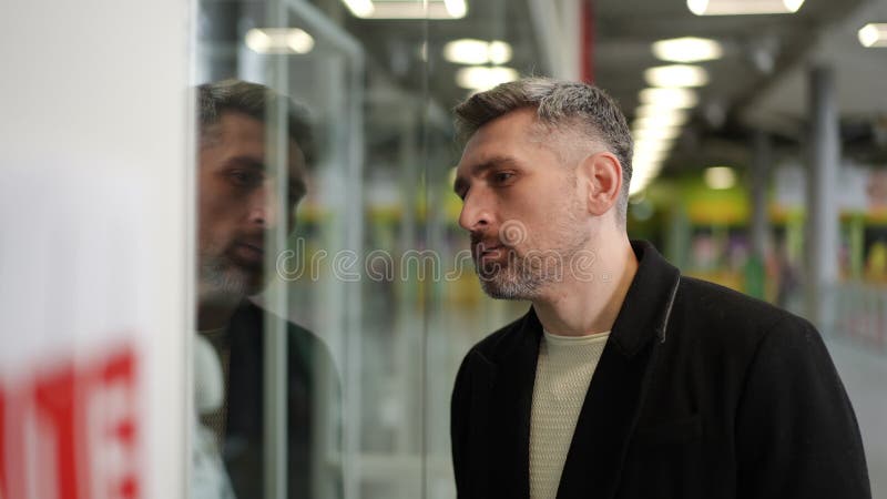 Man Looking at Storefront Display Reflecting in Glass at Shopping Mall ...