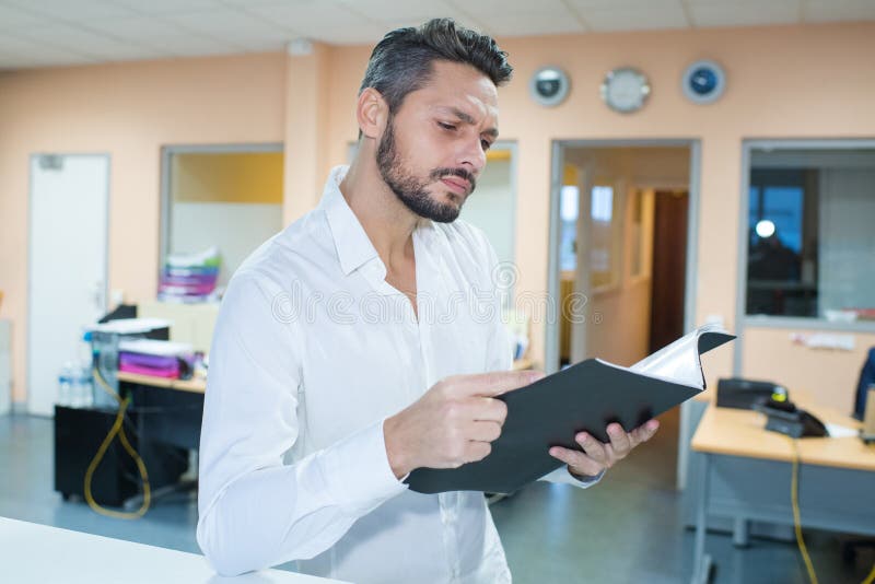 Man in office reading file stock image. Image of file - 173913263