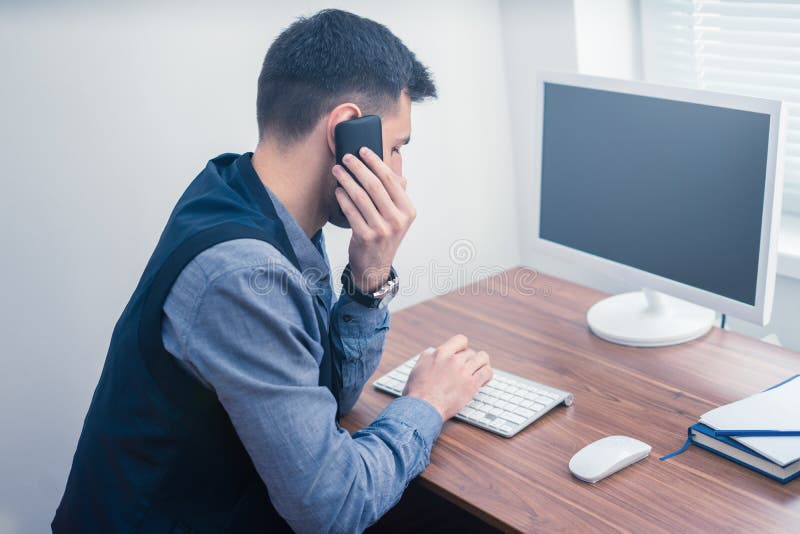 Man in Office on Telephone Using Computer and Typing on Keyboard Stock ...