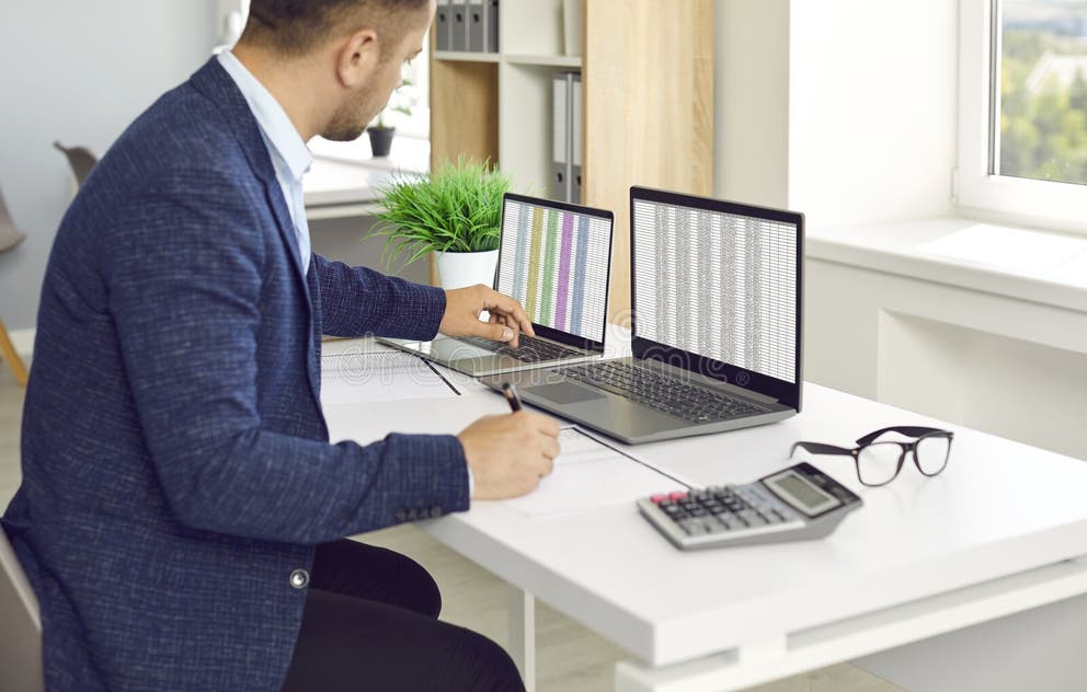 Man in Office Working with Big Data and Databases Using Two Laptops and Excel Tables. Stock ...