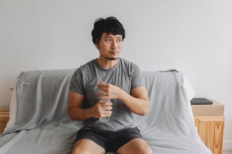 Man Opening the Plastic Bottle of Water while Sitting on the Sofa in ...