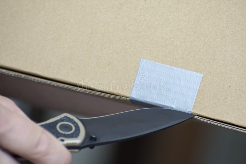 The Man Opens a Cardboard Box with a Knife. Delivery of Mail and ...