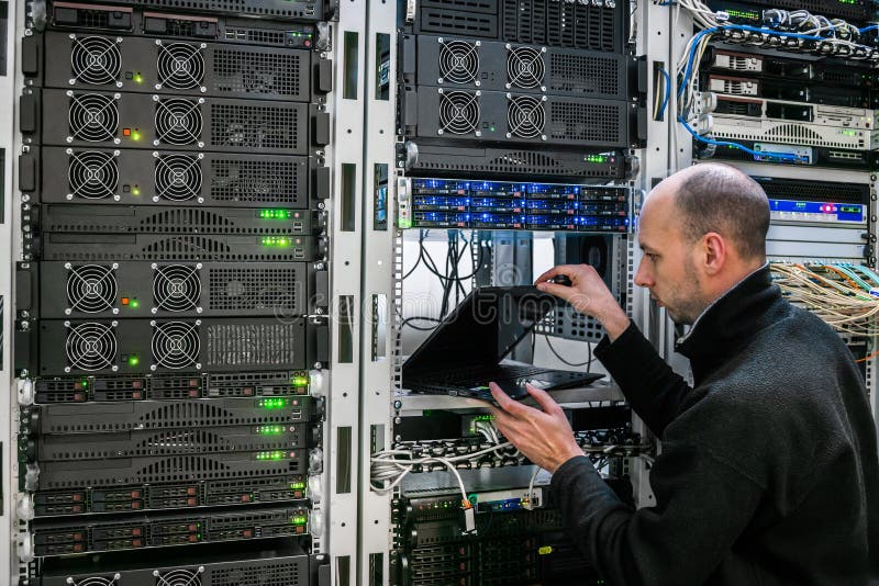 A Man Opens a Laptop Near the Racks with Computer Equipment. the System ...