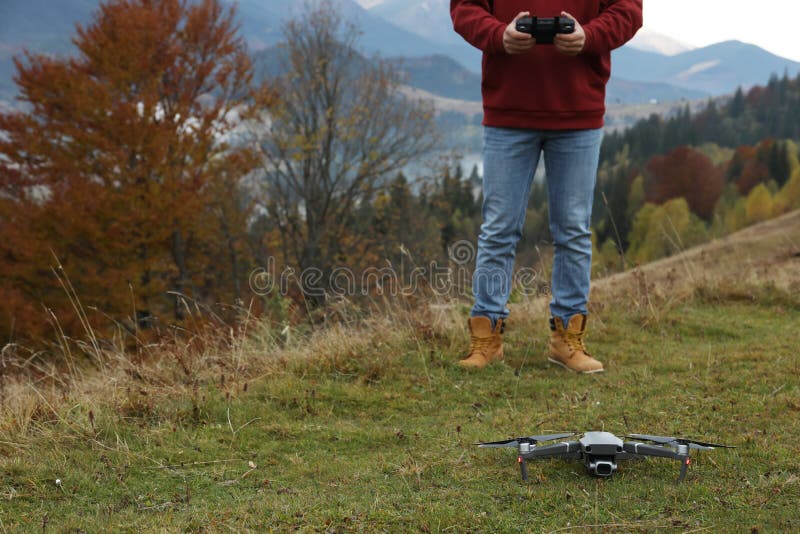 Man Operating Modern Drone with Remote Control in Mountains. Space for ...