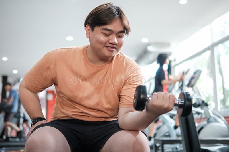 A Man in an Orange Shirt is Lifting a Dumbbell Stock Image - Image of ...