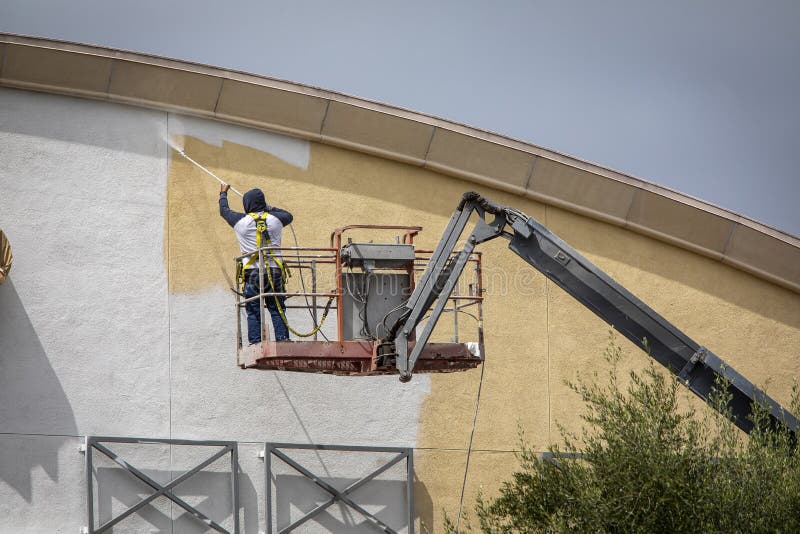 Man Painting a Yellow Wall White Using a Paint Sprayer while Standing ...