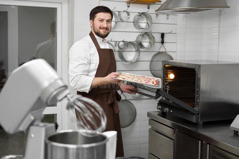 Man Pastry Chef Puts the Sponge Dough in the Oven. Stock Photo - Image ...