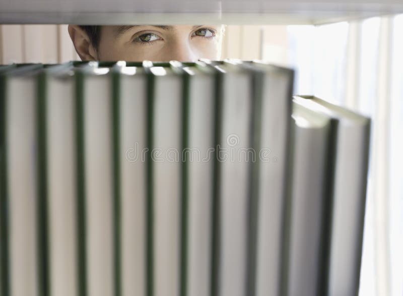 Man Peeking from Behind Books in Library Stock Image - Image of ...