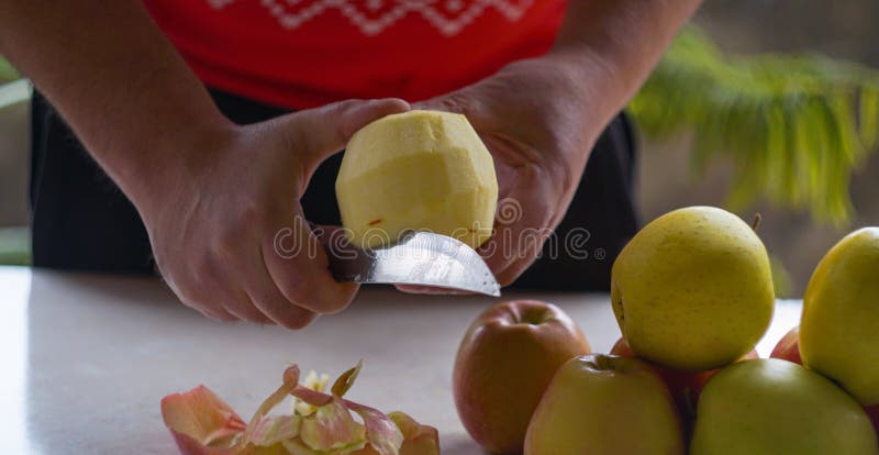 A Man is Peeling an Apple with a Knife on a Table Stock Photo - Image ...