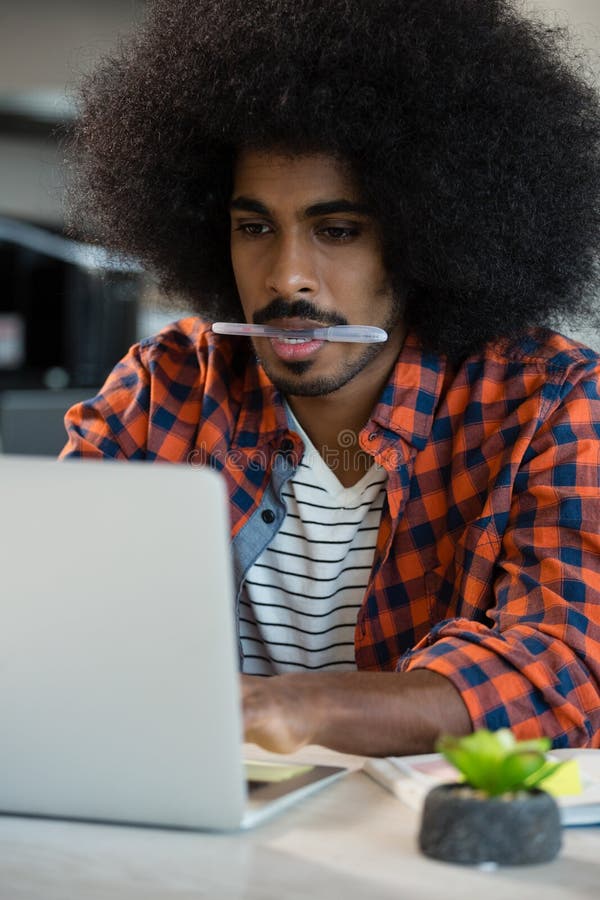 Man with Pen in Mouth Using Laptop in Office Stock Image - Image of ...