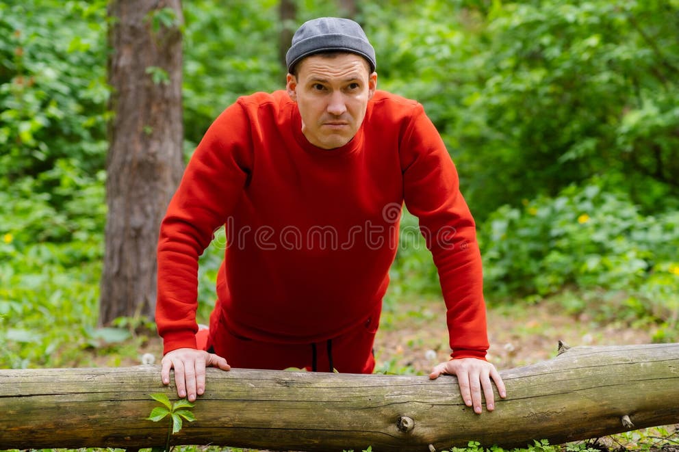 A Man Performs Push-ups Using the Log As Support. the Backdrop is a ...