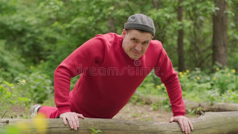 A Man Performs Push-ups Using the Log As Support. the Backdrop is a ...