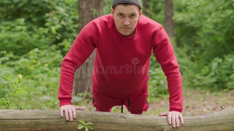 A Man Performs Push-ups Using the Log As Support. the Backdrop is a ...