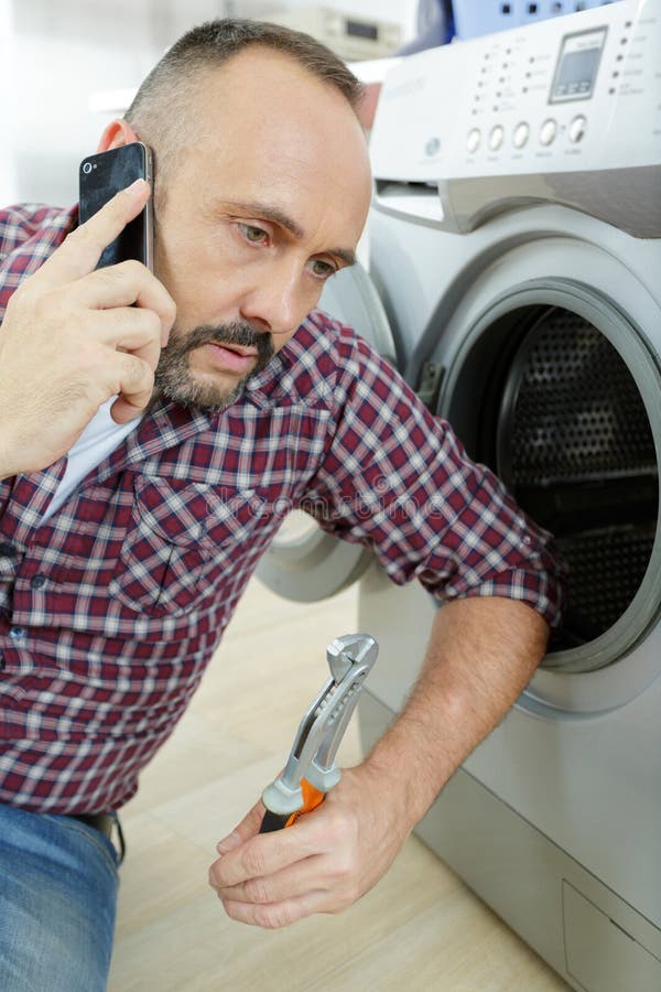 Man on Phone Next To Washing Machine Stock Photo - Image of washing ...