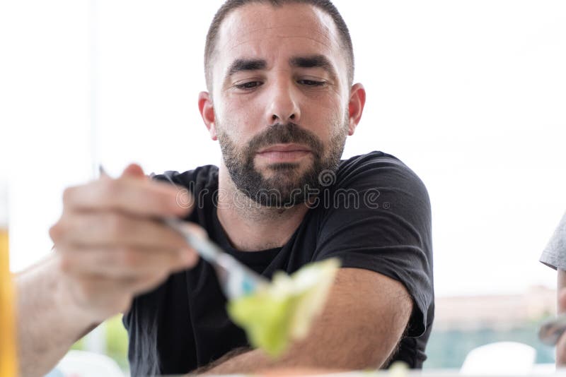 Man Picking Up Salad Food from a Shared Plate in the Middle of a Table ...