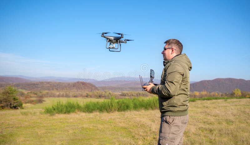 Man Pilots a Drone in Nature by Controlling it from a Remote Control ...