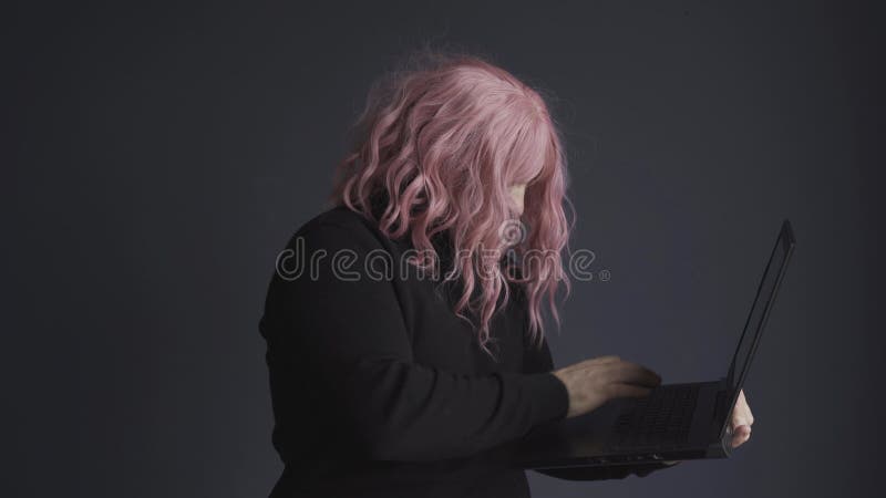 A Man in a Pink Wig Stands and Works at a Computer, Typing. Stock ...