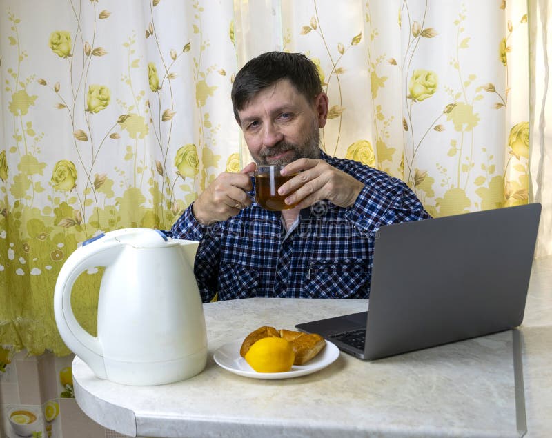 A Man in a Plaid Shirt is Drinking Tea at the Kitchen Table and Smiling ...