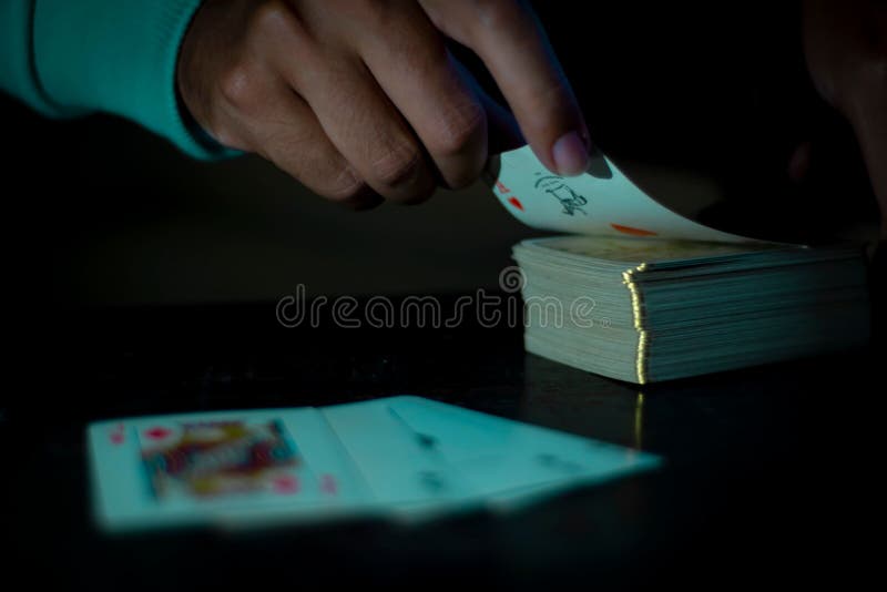 Man Playing with Cards on a Table in a Dark Background Stock ...