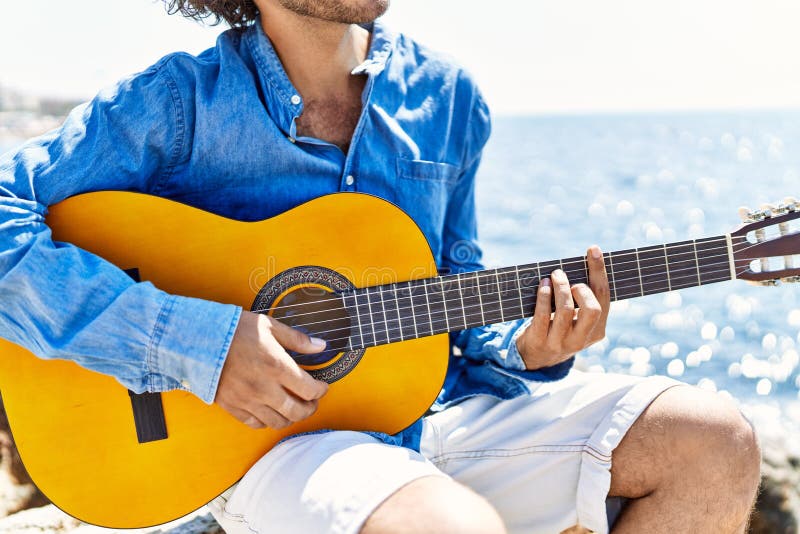 Man Playing Classical Guitar Sitting on Rock at the Beach Stock Photo ...