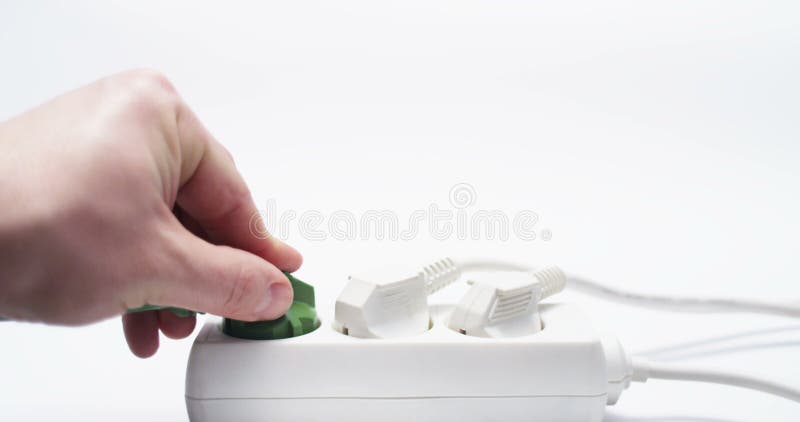 Man Plugging in a Green Extension Cord into a Power Socket As a ...