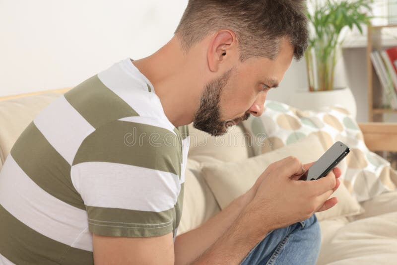Man with Poor Posture Using Smartphone on Sofa at Home Stock Photo ...