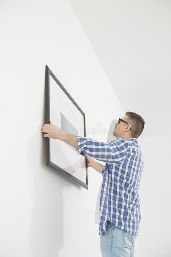 Man Positioning Picture Frame on Wall Stock Image - Image of adult ...
