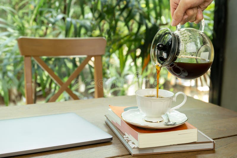 Man Pouring Coffee into a Cup with Laptop on the Table. Stock Image ...