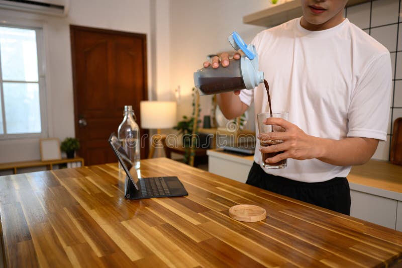 Man Pouring Mixed Chocolate Protein Shake from a Shaker Bottle into a ...