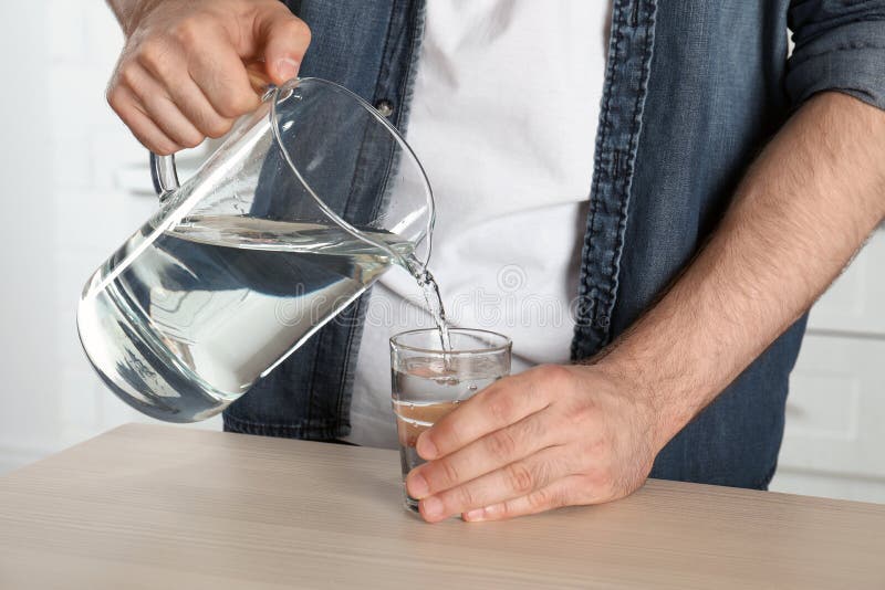 Man Pouring Water into Glass at Table Stock Image - Image of beverage ...