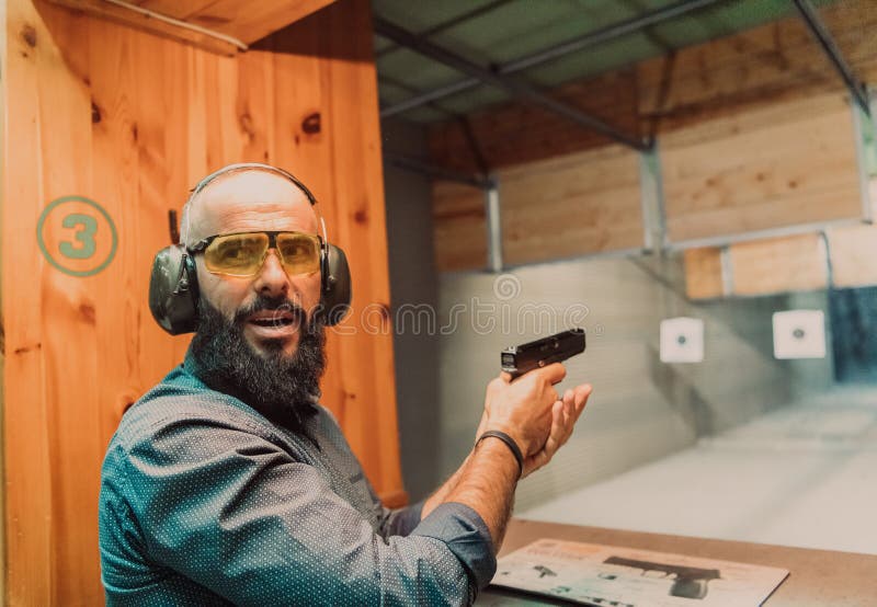 A Man Practices Shooting a Pistol in a Shooting Range while Wearing ...