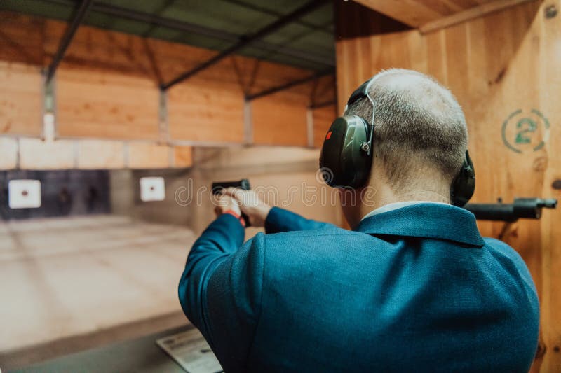 A Man Practices Shooting a Pistol in a Shooting Range while Wearing ...
