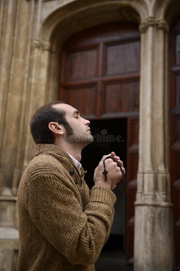Man Praying in Front of the Church Holding a Cross Stock Photo - Image ...
