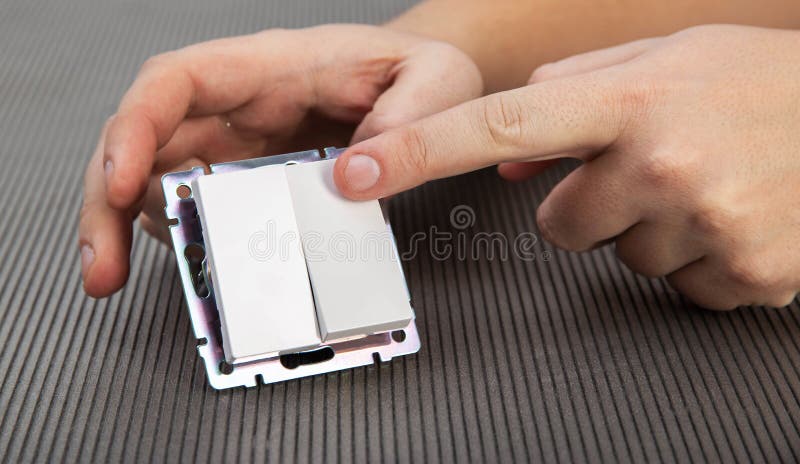 A Man Presses His Finger on a Double Electric Switch on a Gray ...