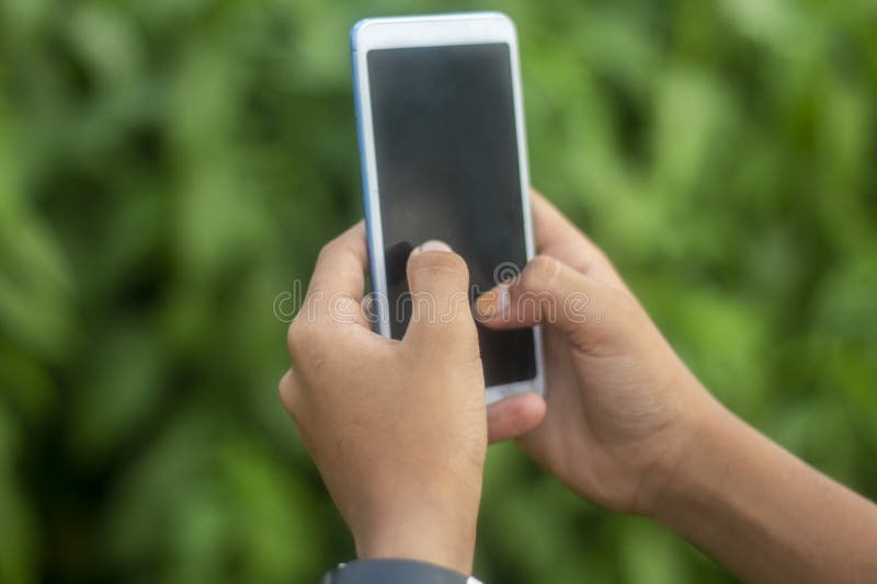 A Man is Pressing a Mobile Phone with His Two Hands and the Background ...