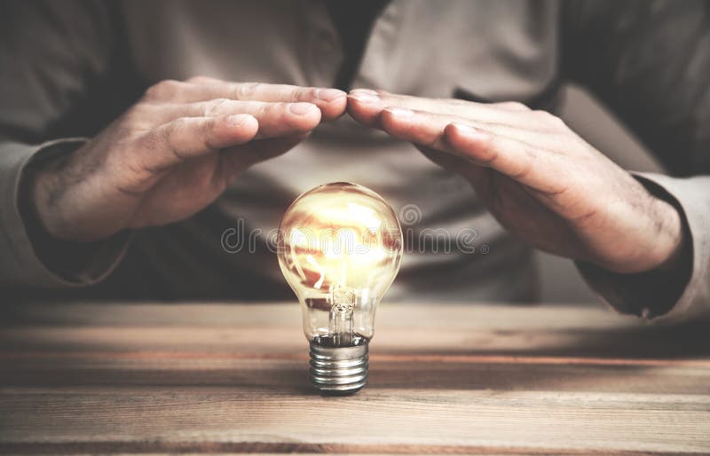 Man protecting light bulb. stock photo. Image of desk - 116076518