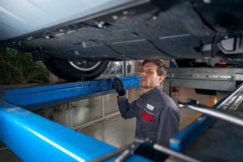 Serviceman Inspecting Wheels Under Auto in the Workshop Stock Photo ...