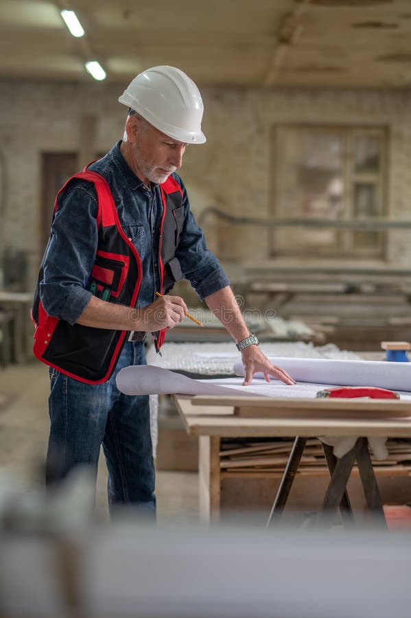Man in Protective Helmet Working in a Workshop with Drawings Stock ...