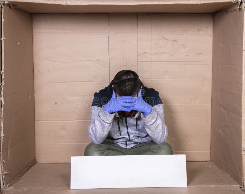 Man in the Protective Mask Sits in a Cardboard Box, he is Totally ...