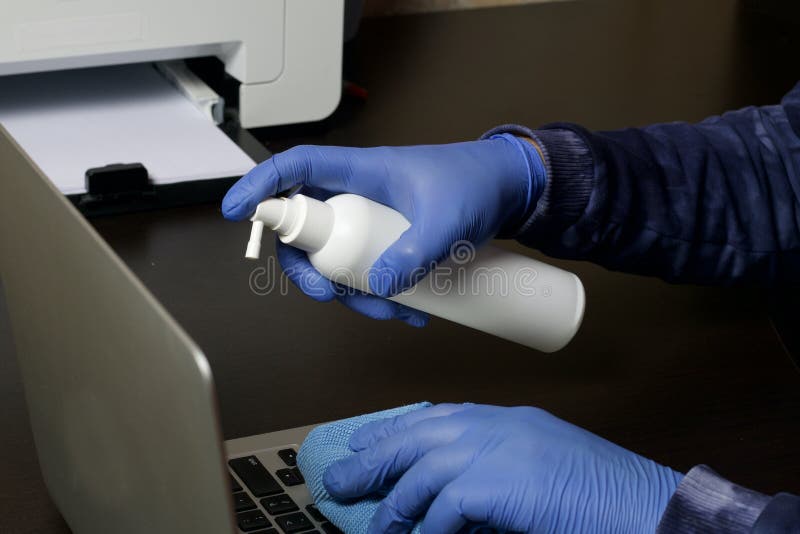 A Man in Protective Rubber Gloves Works at a Laptop. from the Atomizer ...