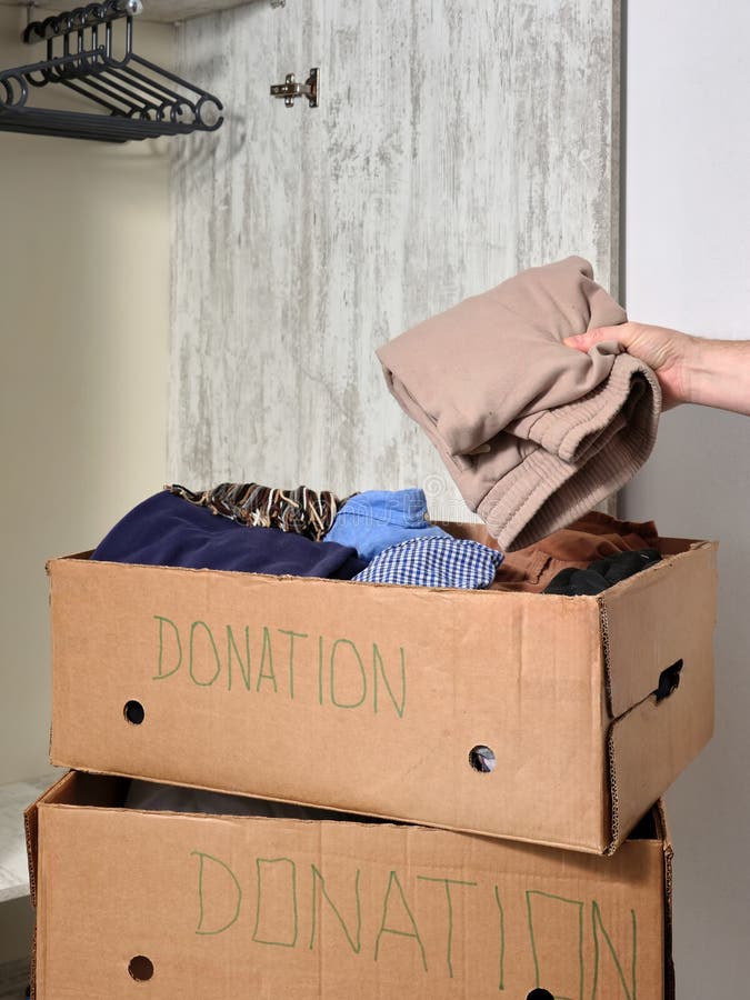 A Man Puts Old Clothes in a Donation Box, with an Empty Clothes Closet ...