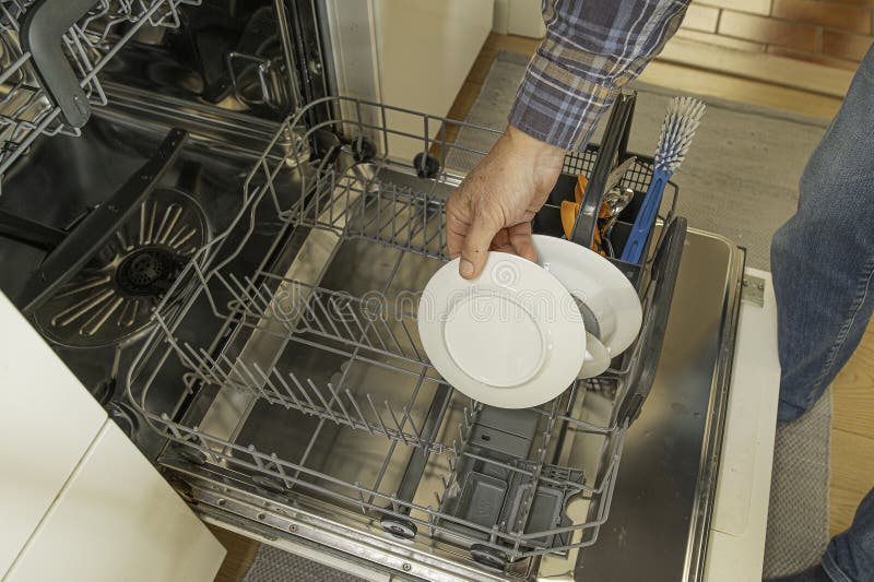A Man Puts a Plate in the Dishwasher in the Kitchen Stock Photo - Image ...