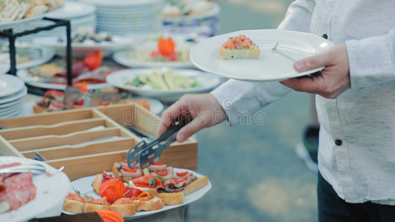 A Man Puts Snacks on a Plate from the Buffet Table. Buffet Table on the ...