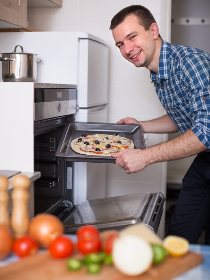 Man Putting a Baking Sheet into the Oven with Pizza Stock Photo - Image ...