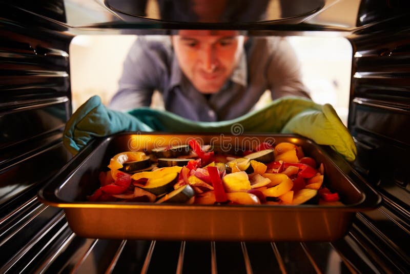 Man Putting Dish of Vegetables into Oven To Roast Stock Photo - Image ...