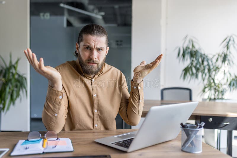 Confused Man in Office Using Laptop and Raising Arms in Question Stock ...