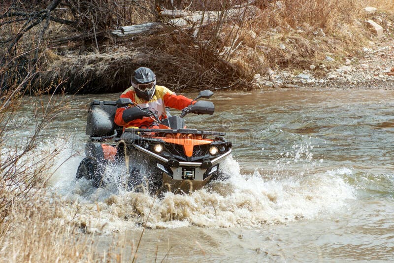 The Man on the Quad Bike Rides on the River with a Splashing Water ...