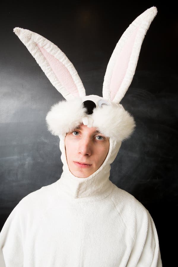 Man in a White Full Body Rabbit Costume Holding a Carrot To His Head ...