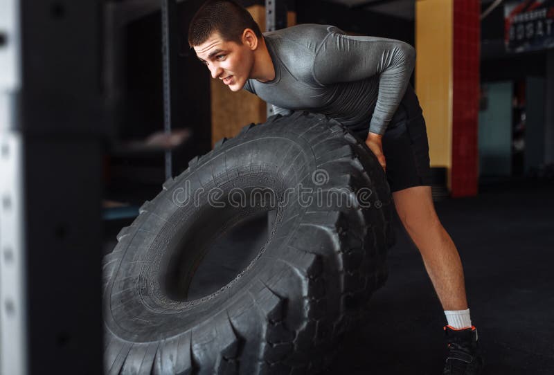 A Man Raises a Big Wheel in the Gym, Training for Muscle Mass Stock ...