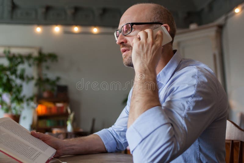 Man Reading Book Indoor and Using Phone Stock Image - Image of business ...